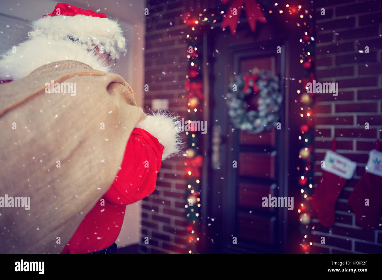 Back of Santa Clause with sack with gifts in front door Stock Photo - Alamy