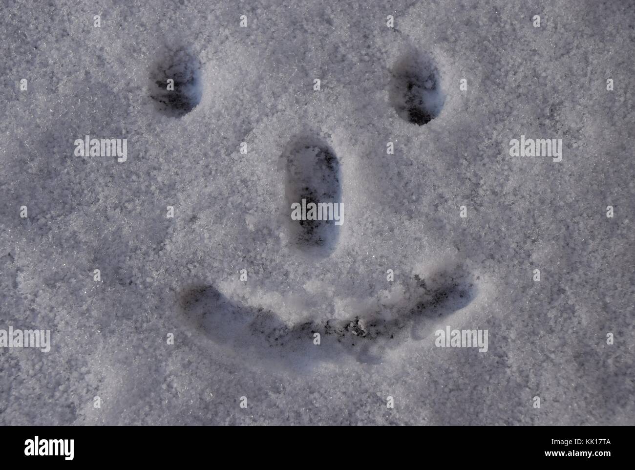 smiley face drawing in the snow on a sunny day Stock Photo - Alamy