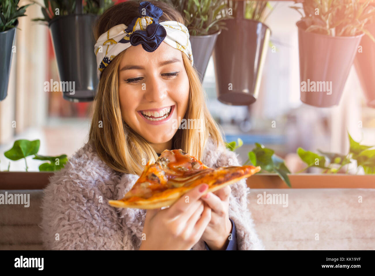 Beautiful happy young woman eating a slice of pizza in the restaurant ...