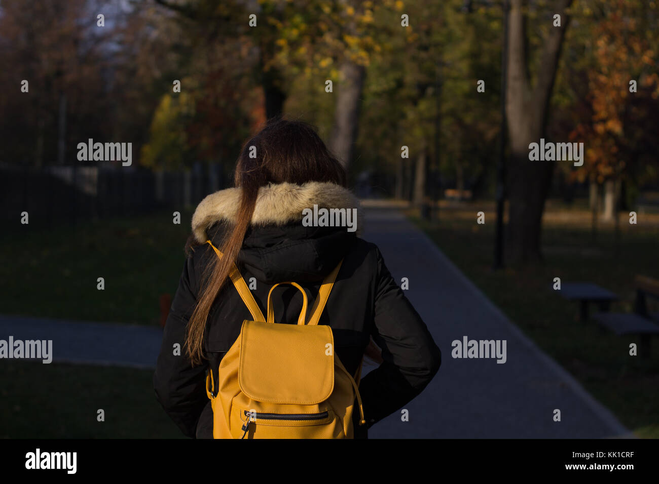 girl with backpack walking at a park with jacket and yellow bag from ...