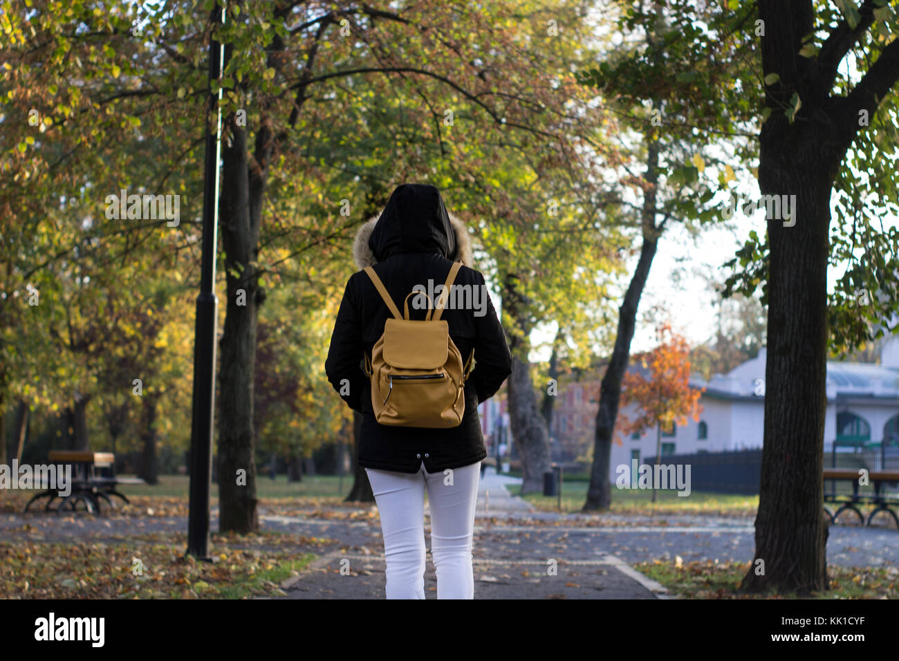 girl with backpack walking at a park with jacket and yellow bag from ...
