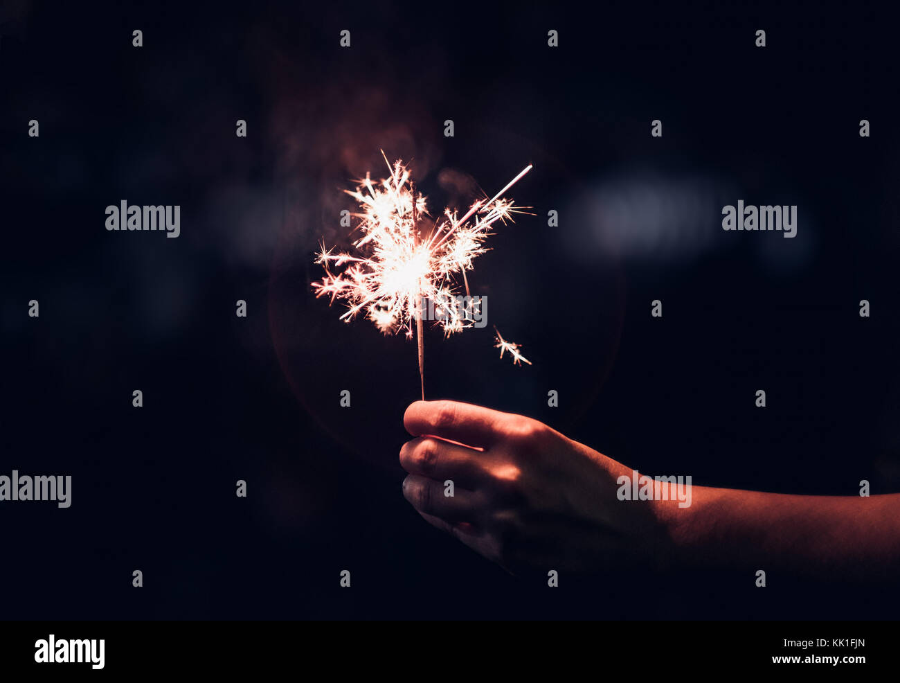 Hand holding burning Sparkler blast on a black background at night ...