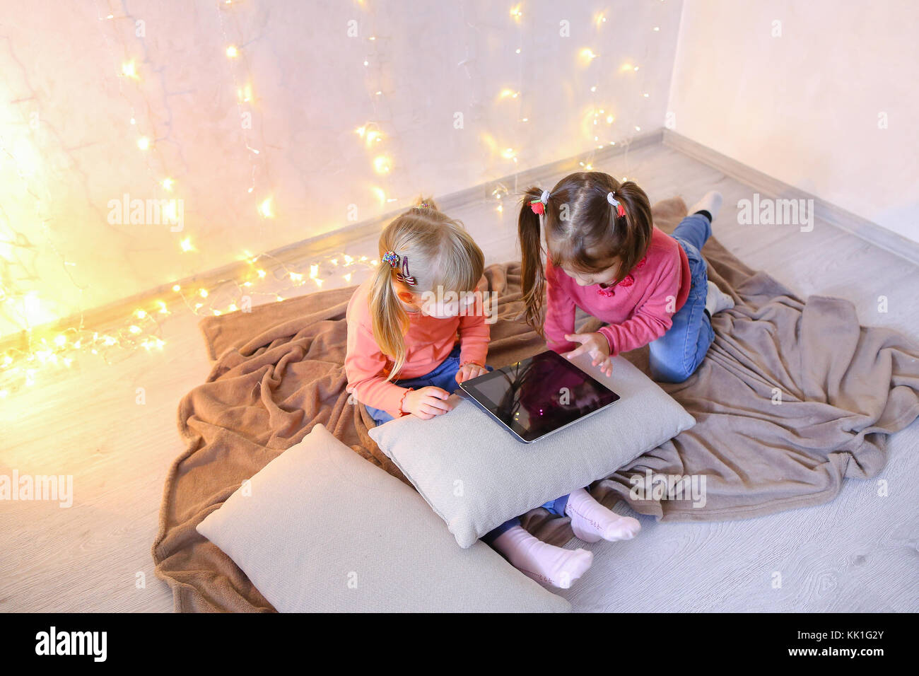 Little girls involved in use of tablet and sit on floor in brigh Stock ...