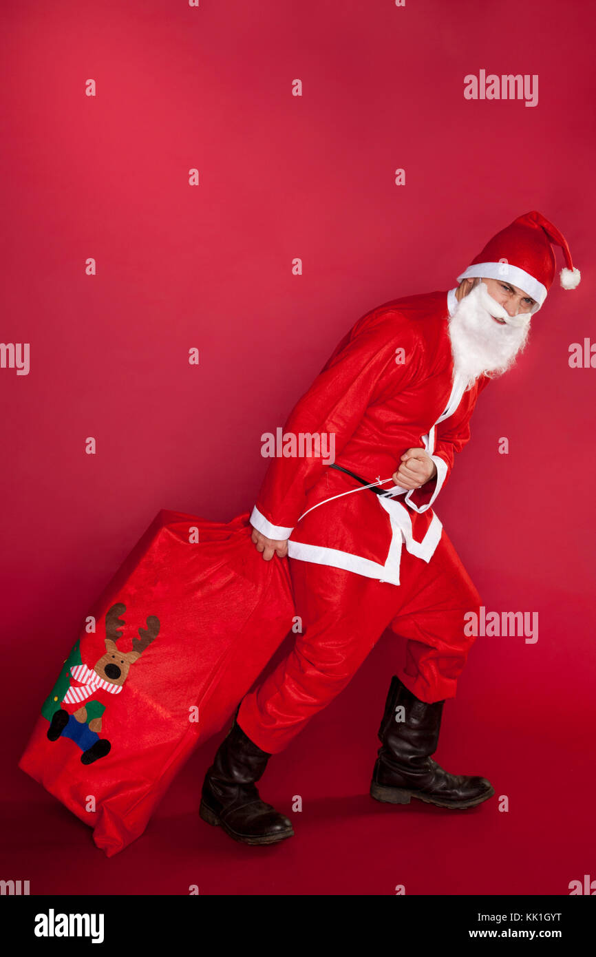 Disappointed Santa Claus pulls a bag stuffed with presents Stock Photo ...