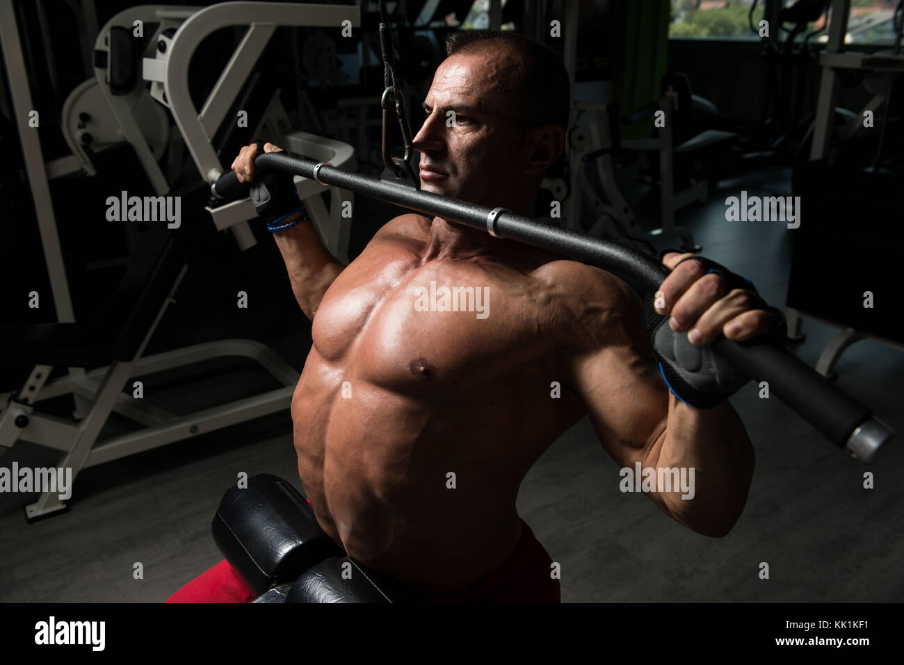 Handsome Bodybuilder Doing Heavy Weight Exercise For Back On Machine ...