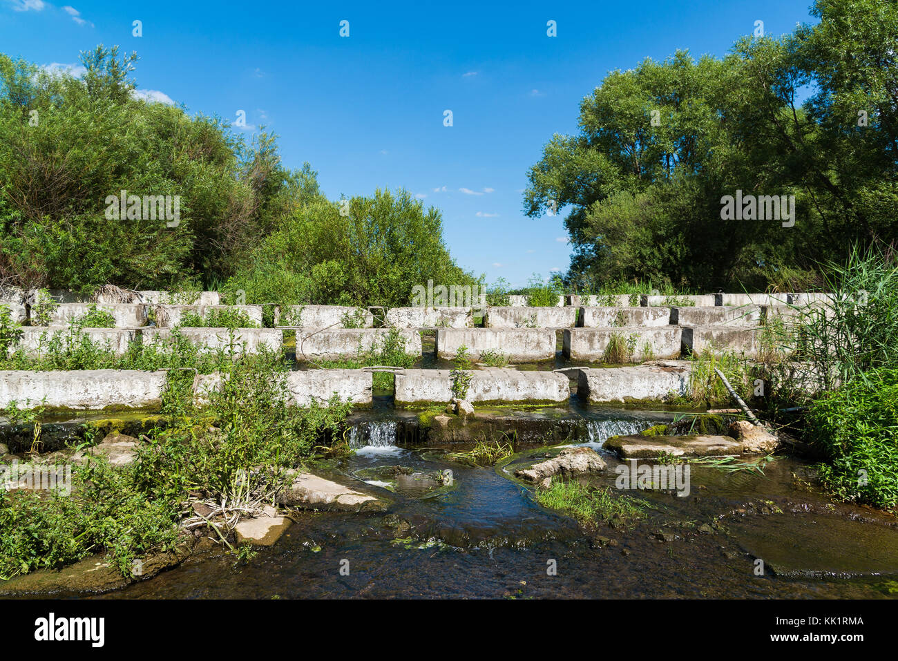 Concrete blocks lying on a small river - dam Stock Photo - Alamy