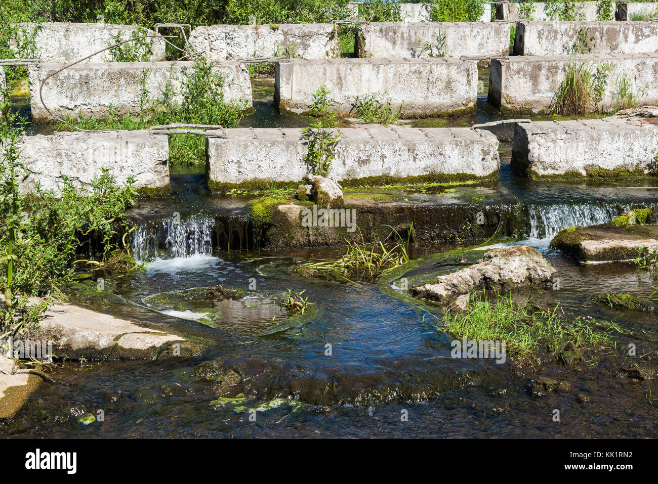 Concrete blocks lying on a small river - dam Stock Photo - Alamy