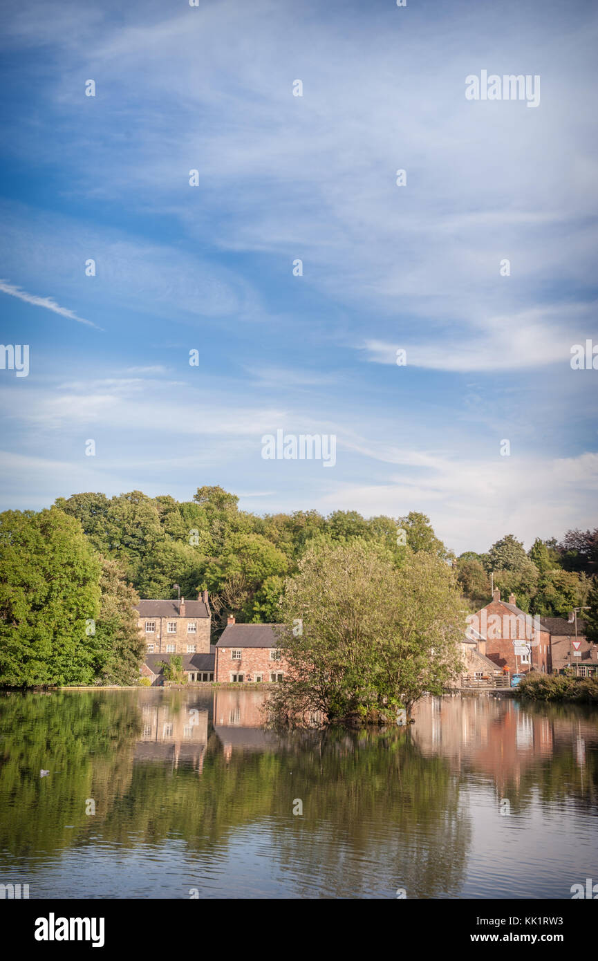 A late afternoon view of the village of Cromford over a mill pond in ...