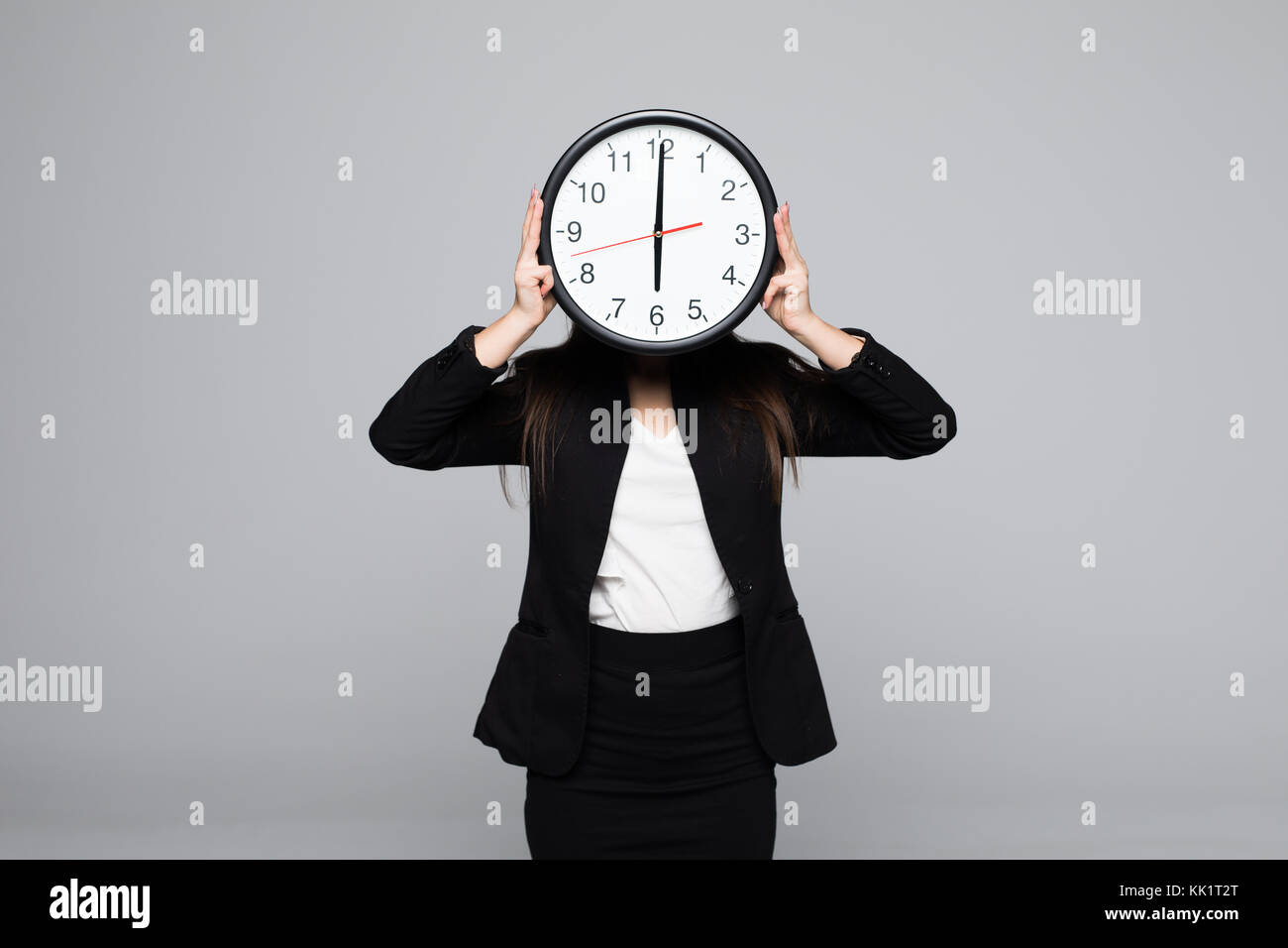 Business woman in suit which holding clock in hands and looking up ...