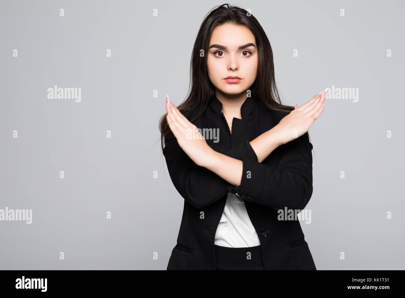 Woman showing a stop arms crossed. On a gray background Stock Photo - Alamy
