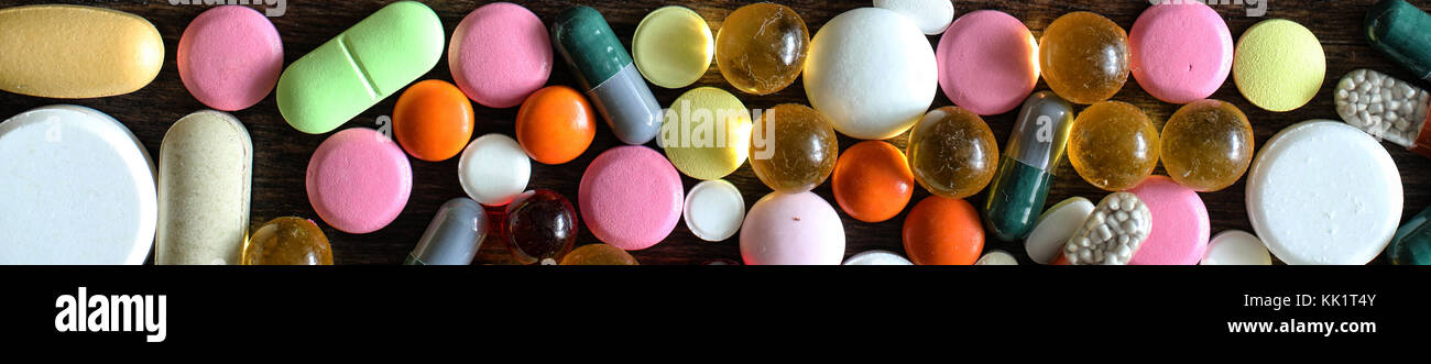 Medical background of various colorful medications on a textured wooden ...