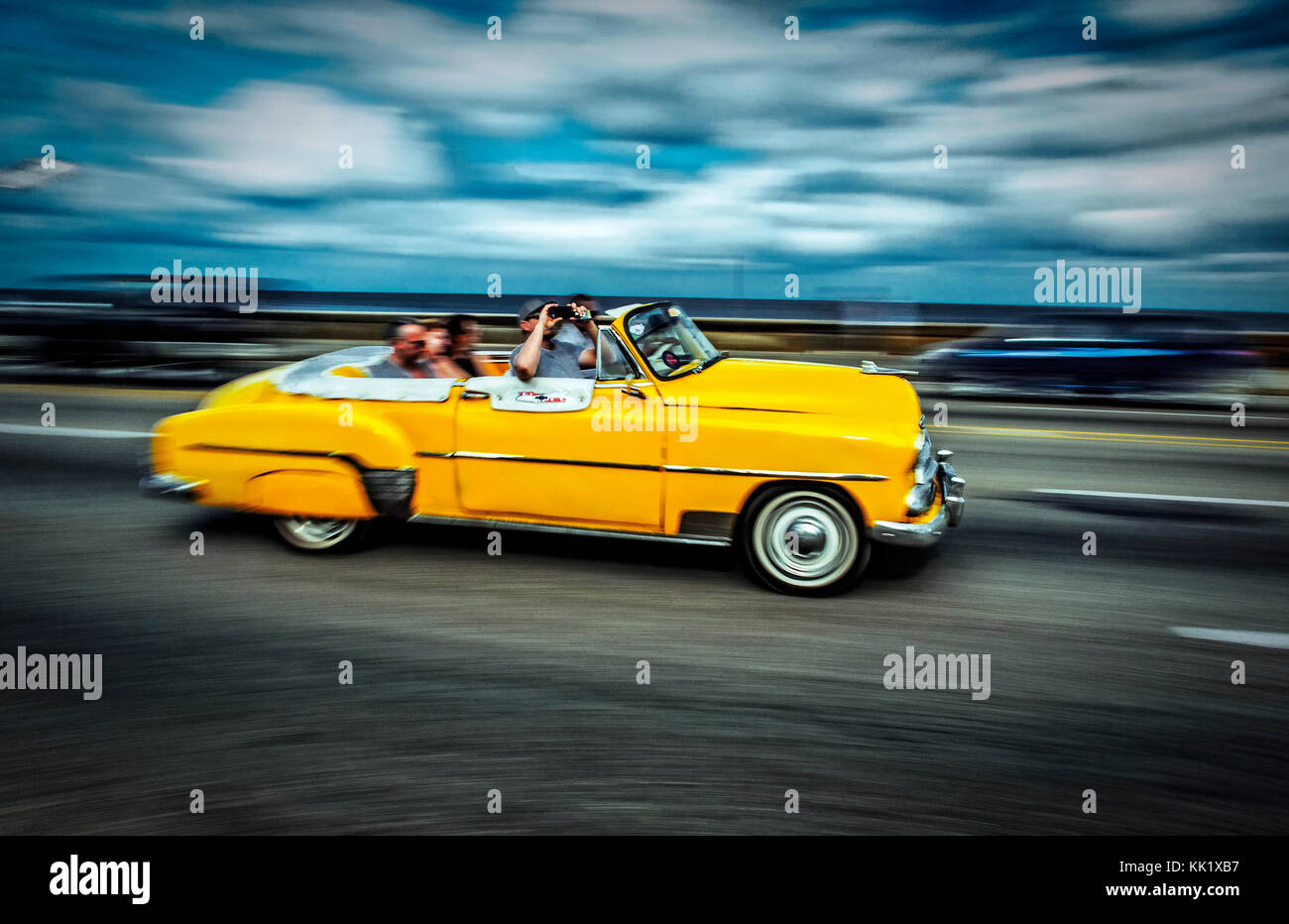 An old yellow car runs along the Malecon of Havana, Cuba Stock Photo ...