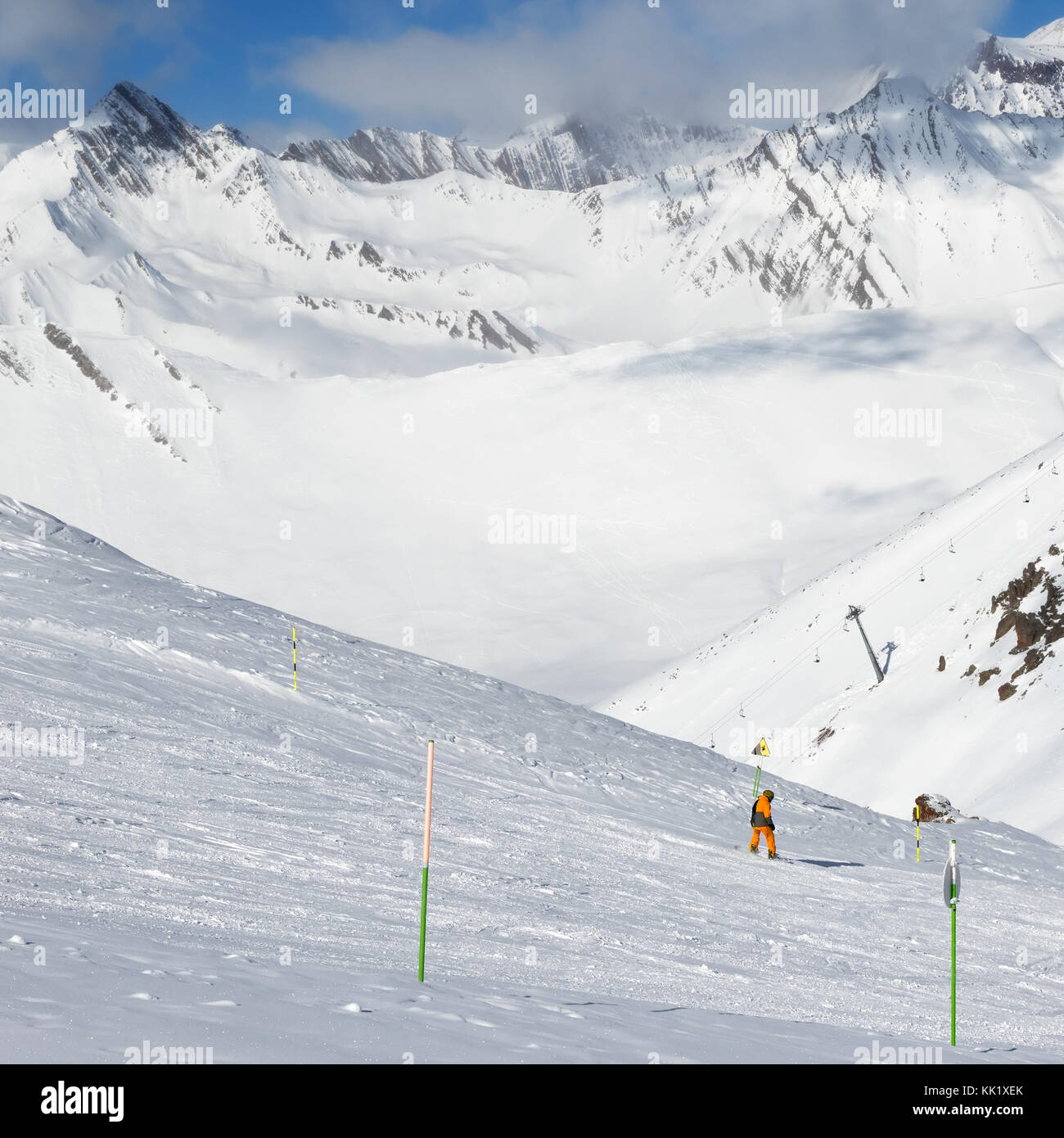 Snowboarder downhill on freeride trace and mountains in clouds at sun ...