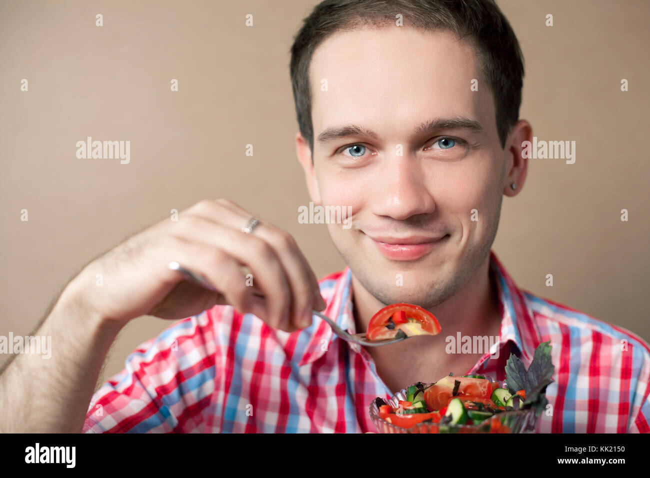 Close-up portrait of a slim handsome boy eating salad over wooden ...