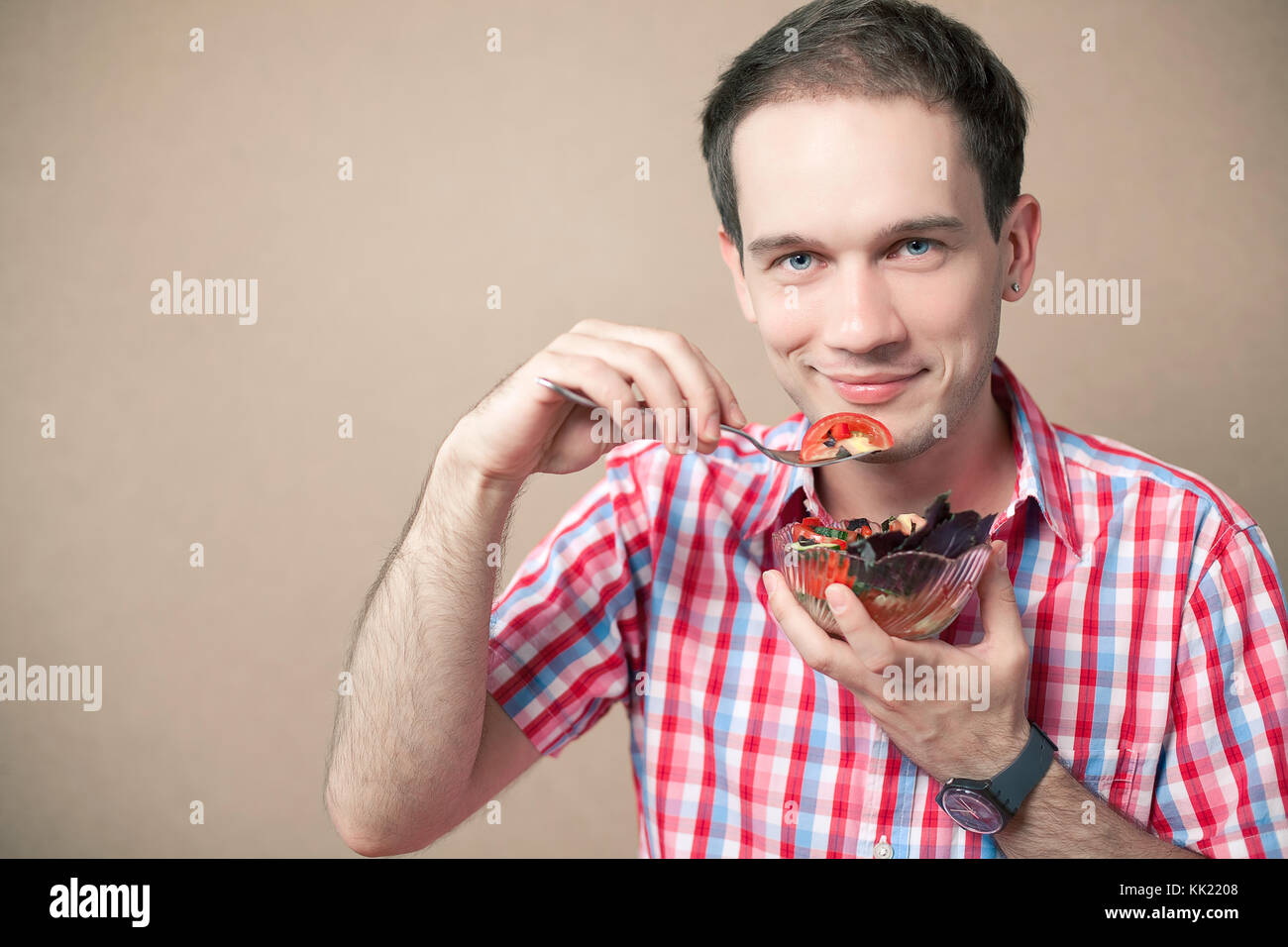 Slim handsome boy eating salad over wooden background. Portrait with ...