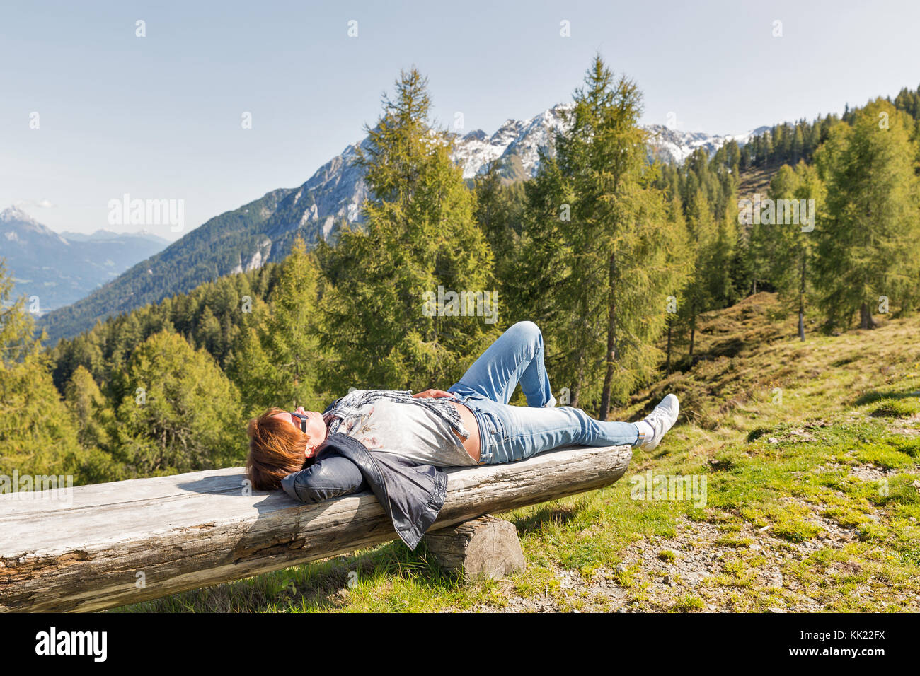 Caucasian middle aged woman have a rest on wooden bench with Alpine ...
