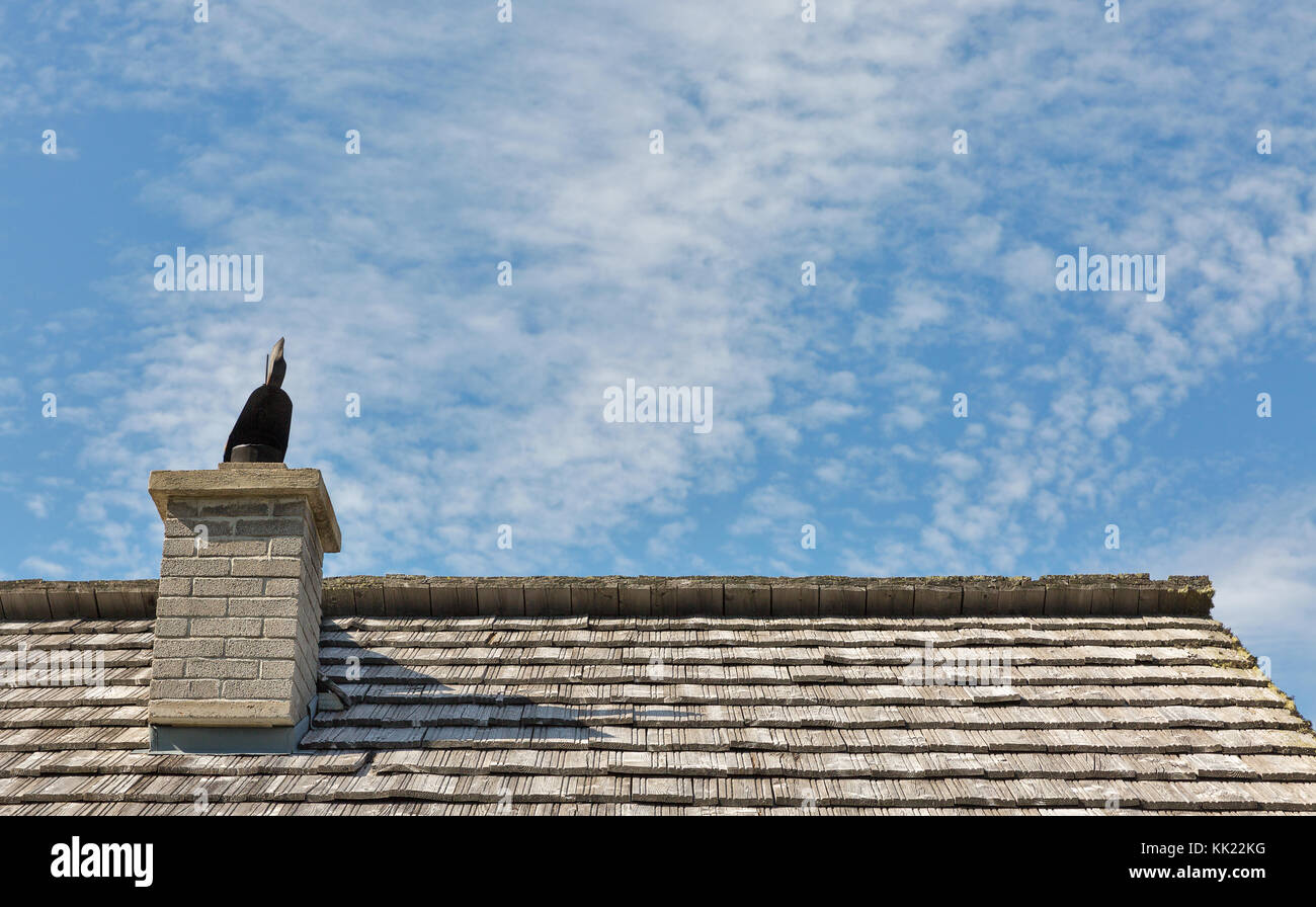 Old wooden lodge roof with chimney and blue sky in Alpine mountains ...