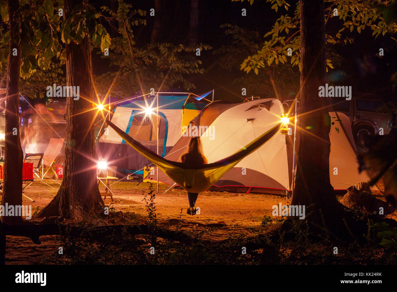 Amazing scene in night camping -girl in hammock on tents background ...