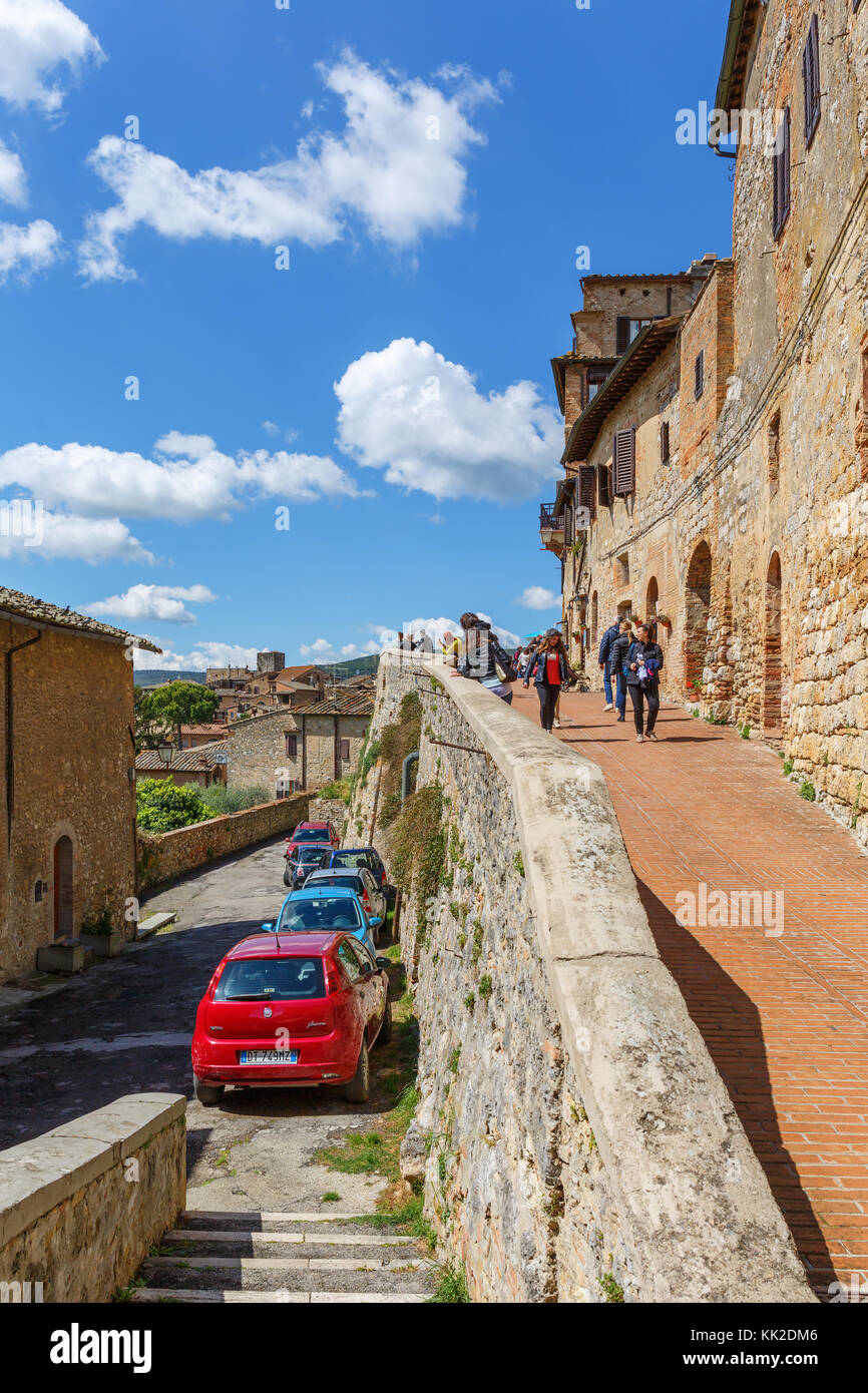 Street with parked cars and people walking on the sidewalk in an ...