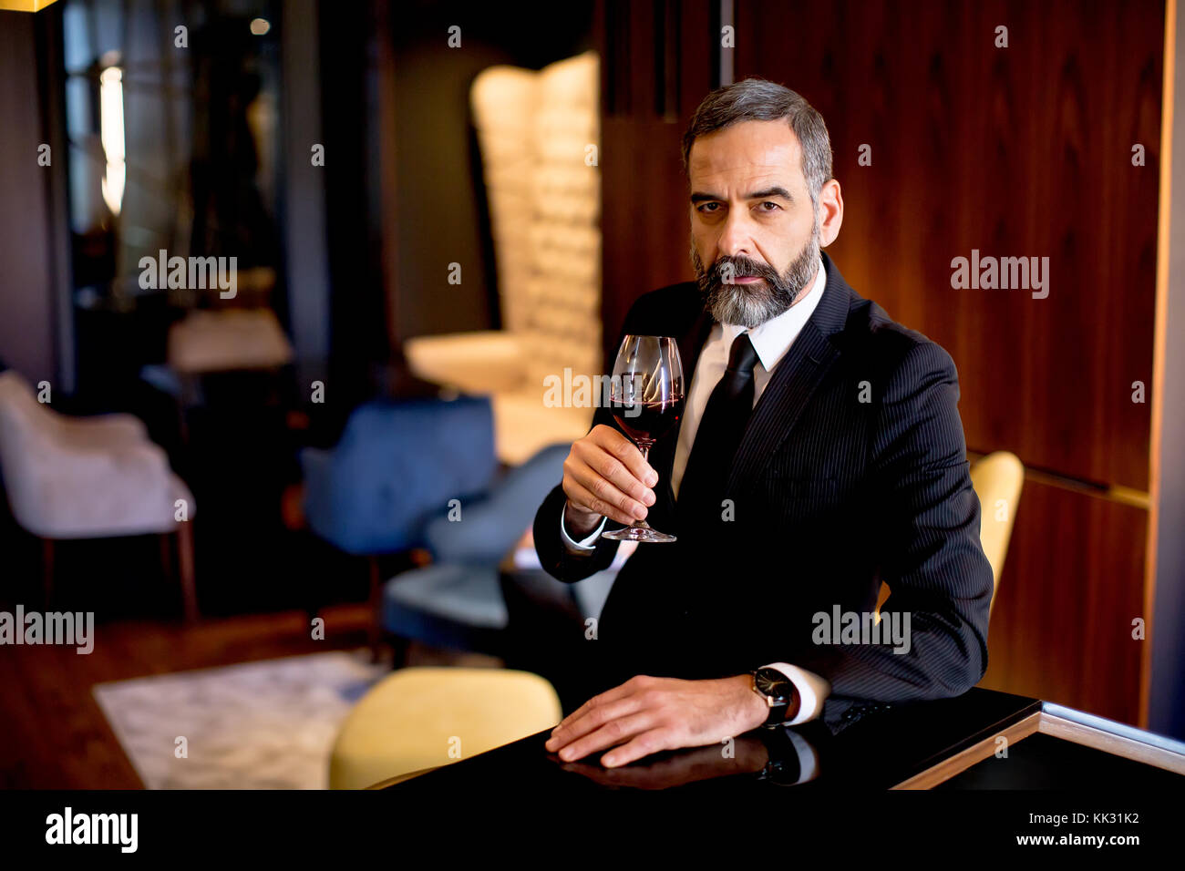 Handsome elegant businessman drinking red wine in bar Stock Photo - Alamy