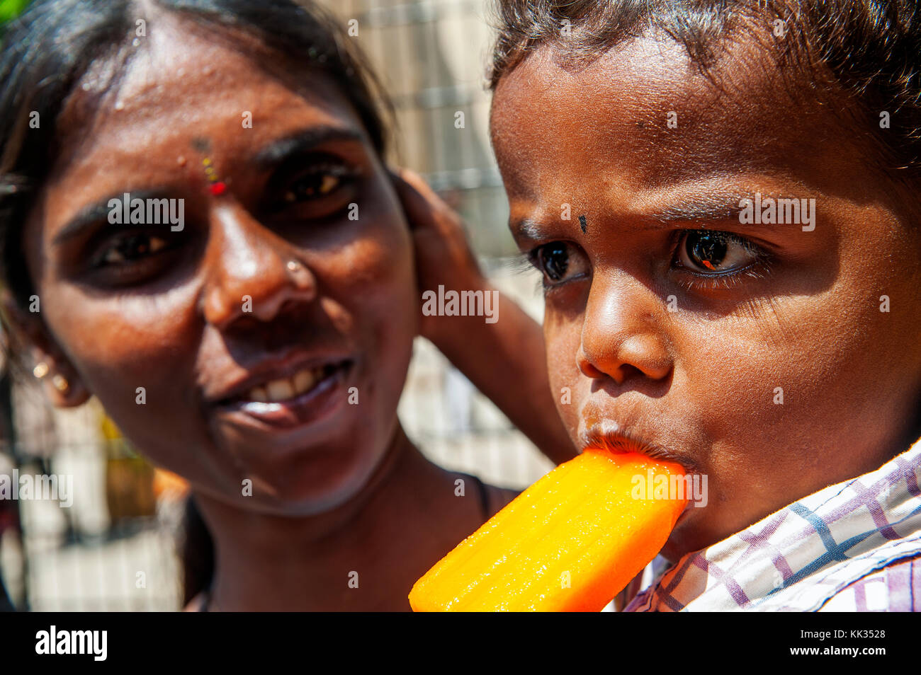 Indian woman with his son enjoying a popsicle in front of Chitradurga ...