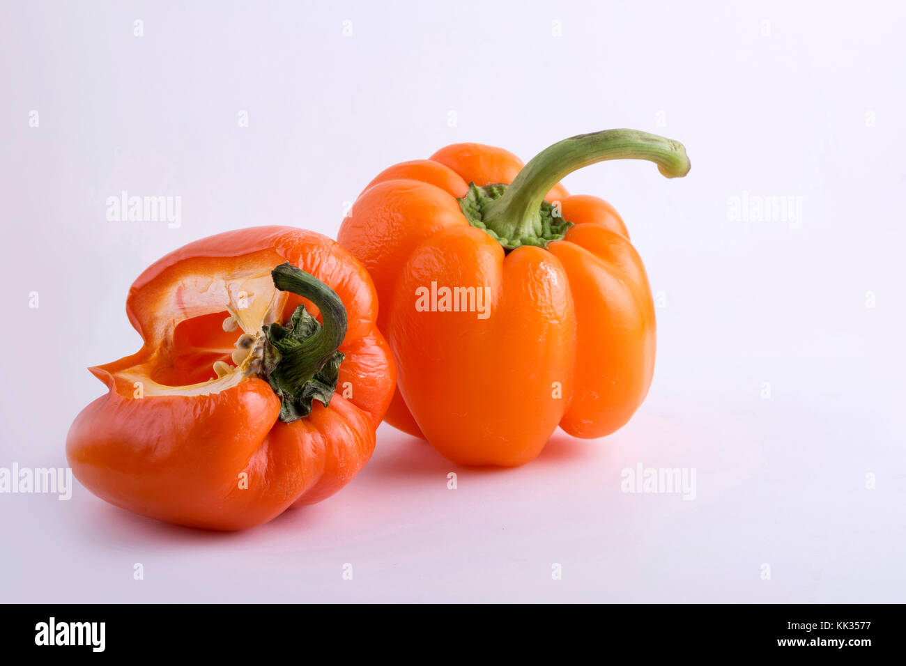 fresh orange bell pepper (capsicum) and a cut one on a white background ...