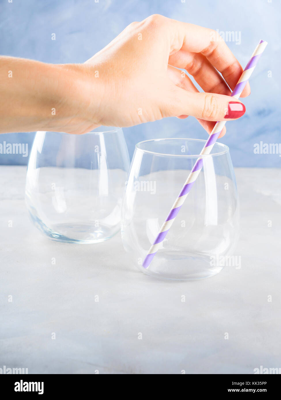 Woman's hand putting party straw in an empty glass Stock Photo - Alamy