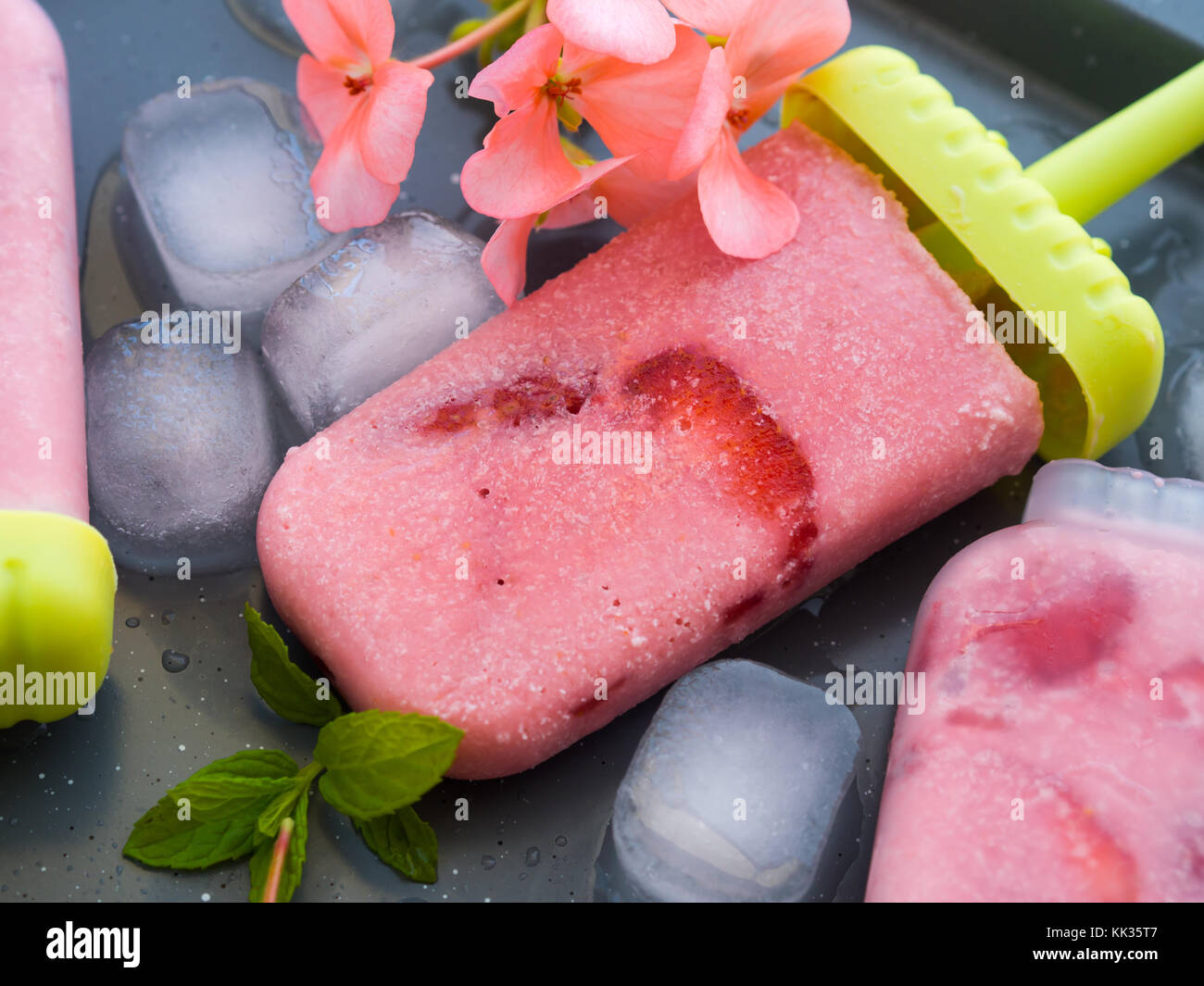 Home made strawberry ice cream popsicles on metall tray with ice cubes ...