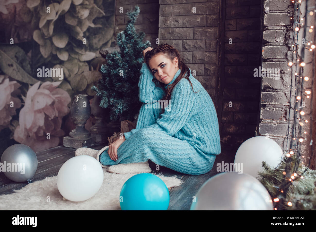 Beautiful woman sits at home near window with christmas lights. New ...