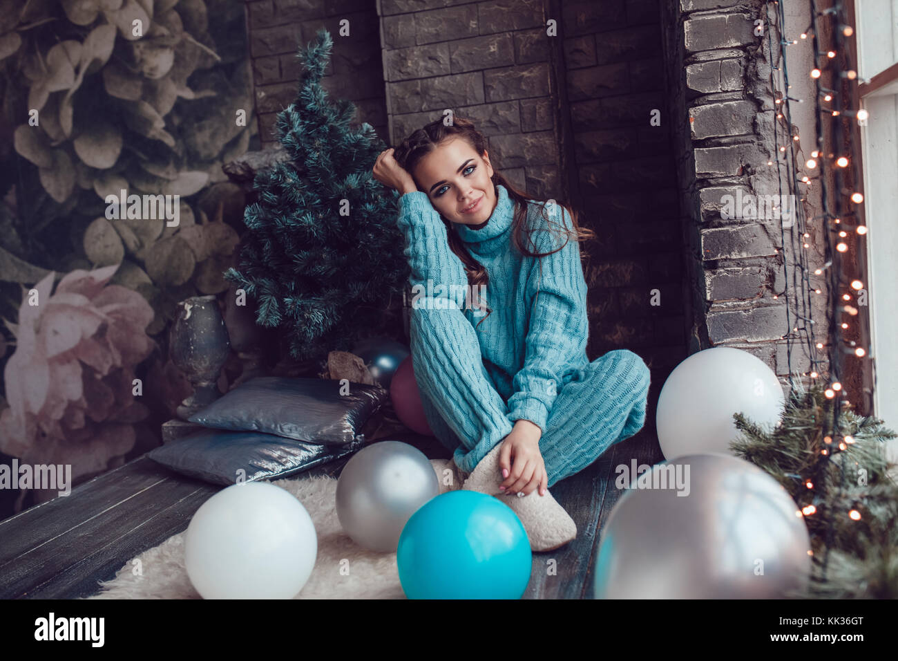 Beautiful woman sits at home near window with christmas lights. New ...