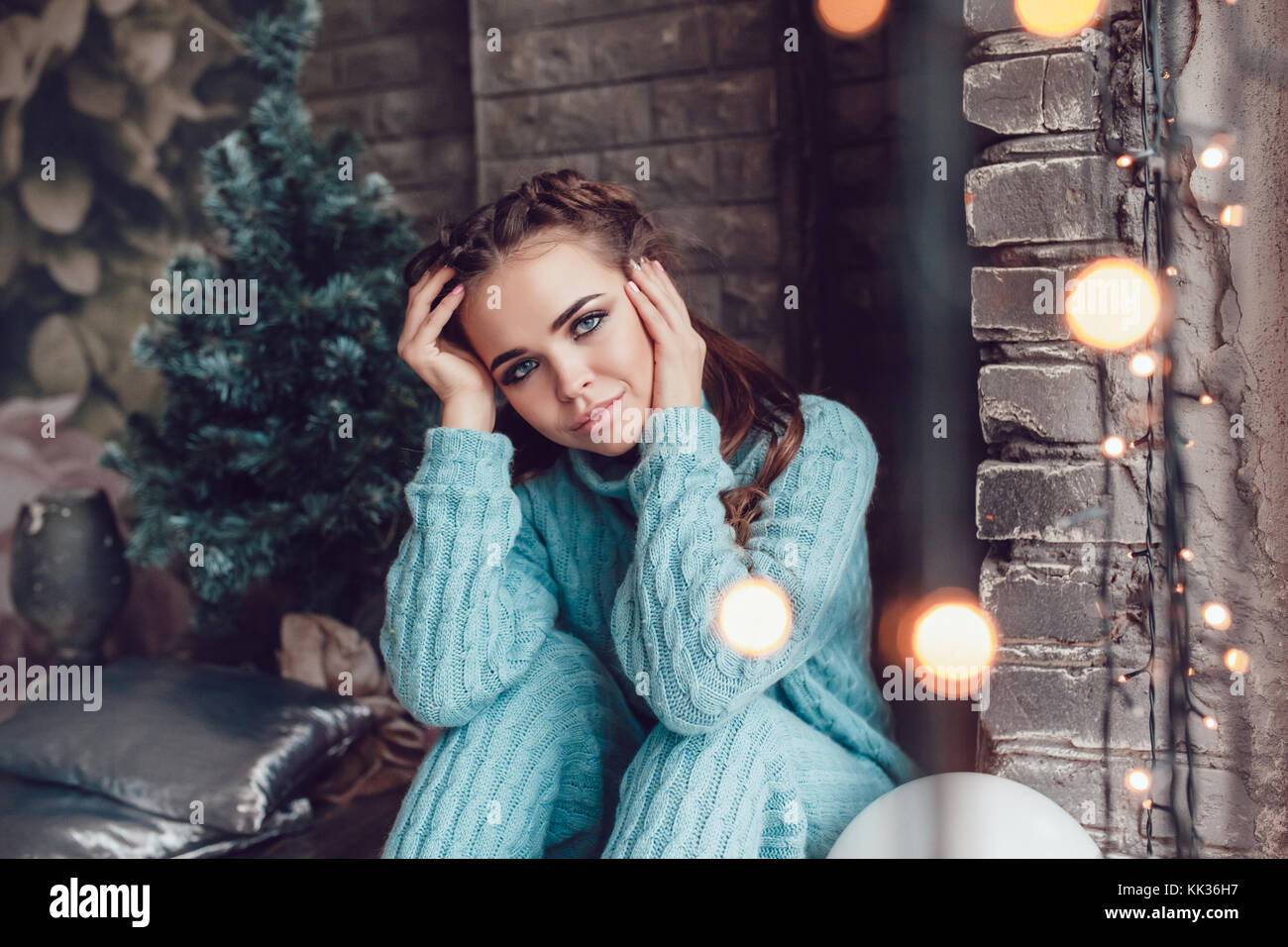 Beautiful woman sits at home near window with christmas lights. New ...