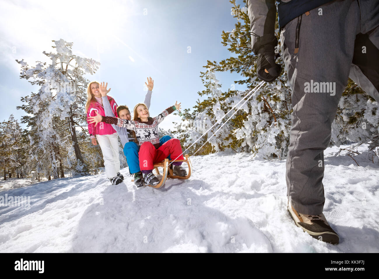 Cheerful children with hands up sitting on sledge together Stock Photo ...