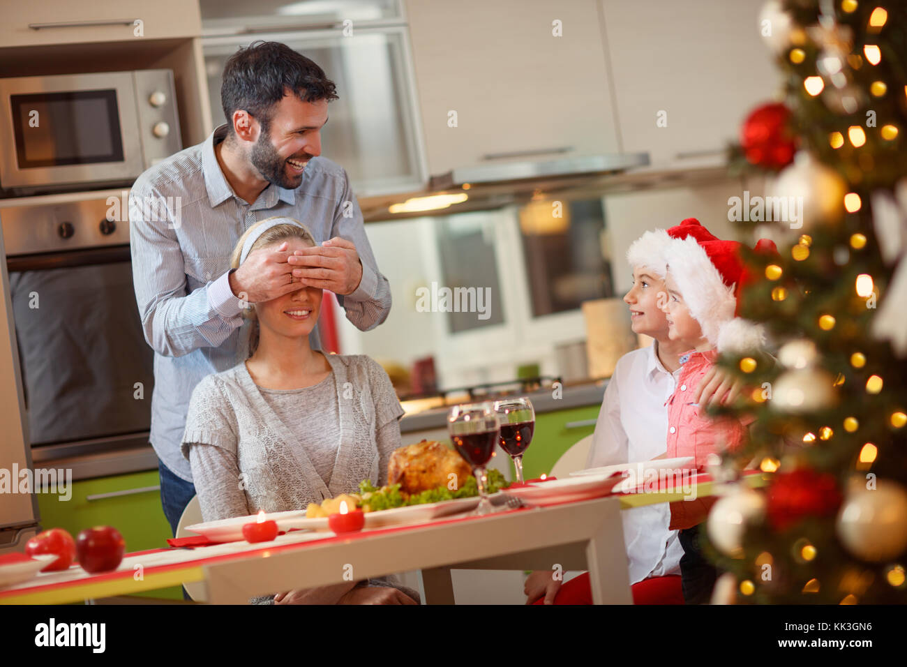 Christmas dinner- happy smiling father and children surprises mother ...