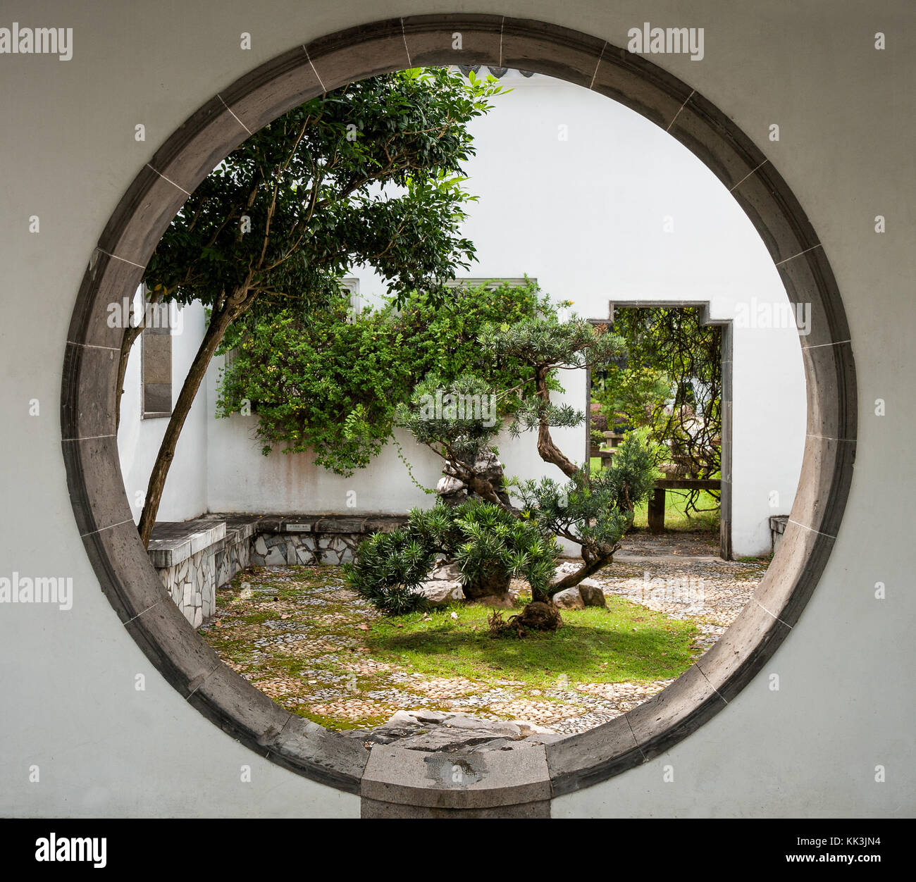 Singapore, Chinese bonsai garden. Wall with a circular hole between the ...
