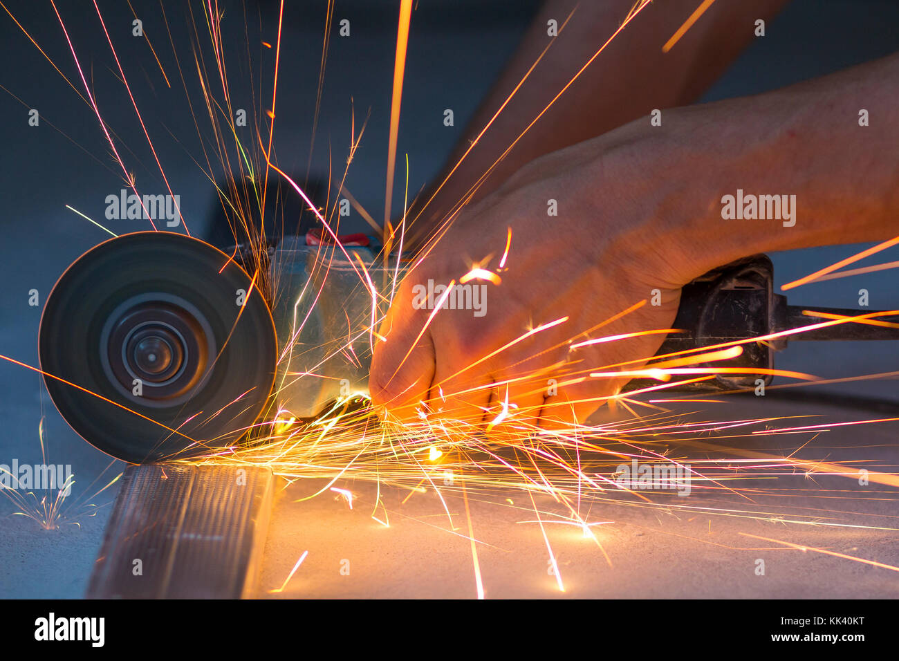 Close-up of worker hands cutting metal with grinder. Sparks while ...