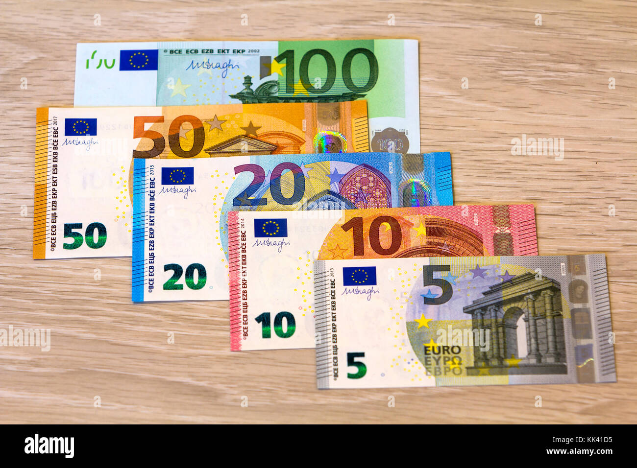Different euro money banknotes on wooden background Stock Photo - Alamy