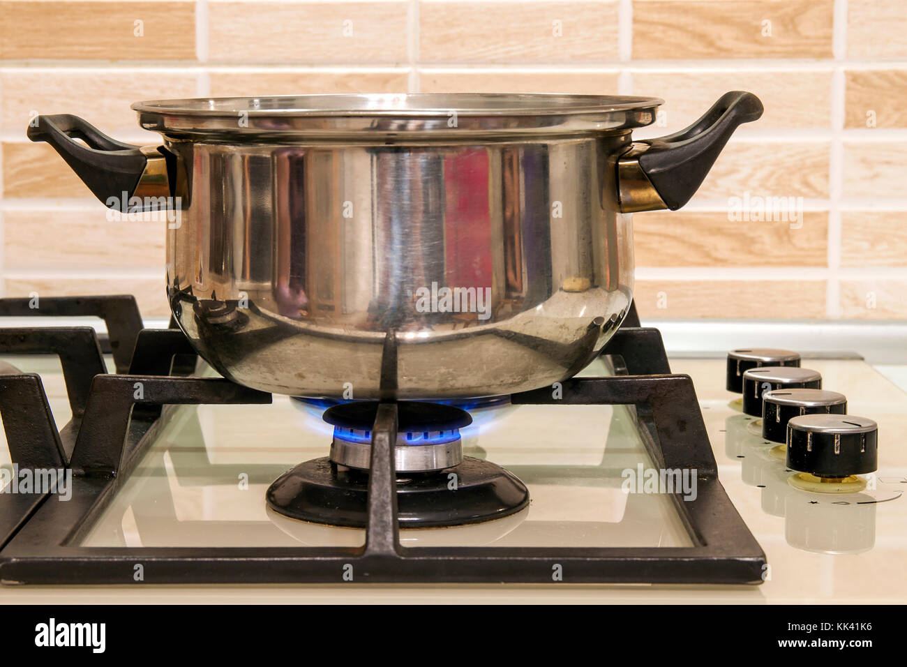 Metal cooking pot standing on kitchen stove with flame Stock Photo - Alamy