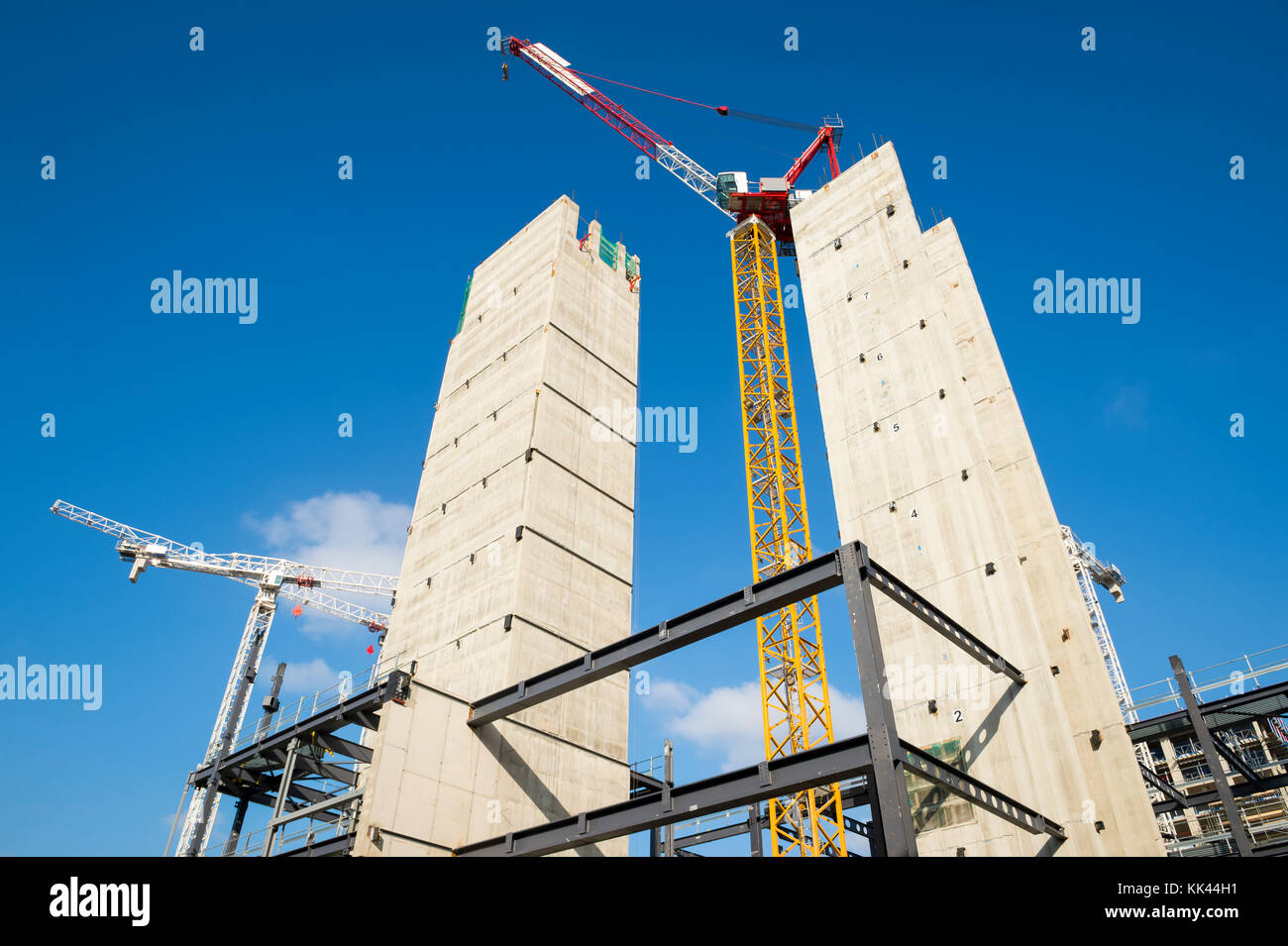 Modern hi-rise towers construction site with cranes under bright blue ...