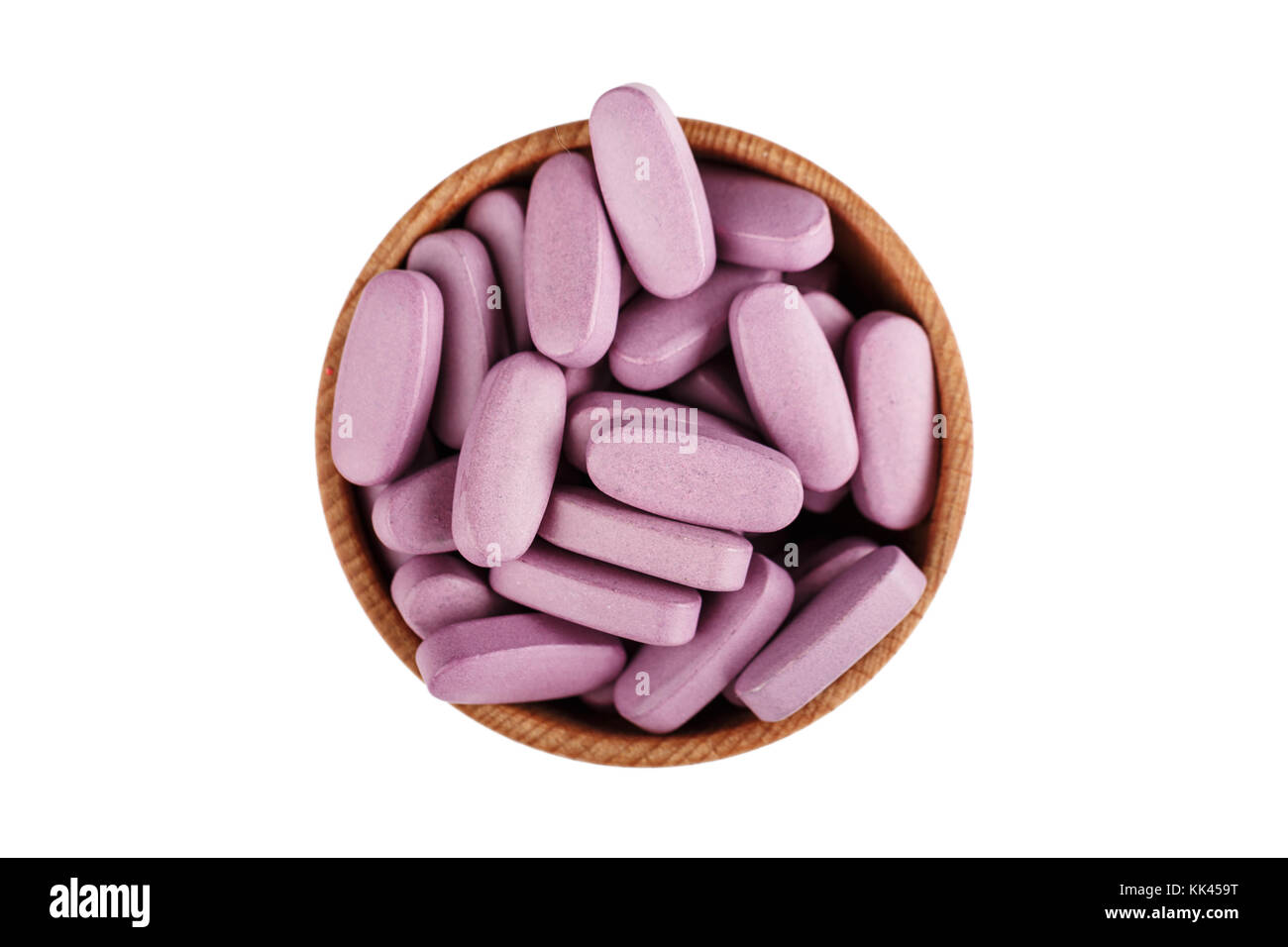 large pink pills in a wooden plate isolated on a white background Stock ...