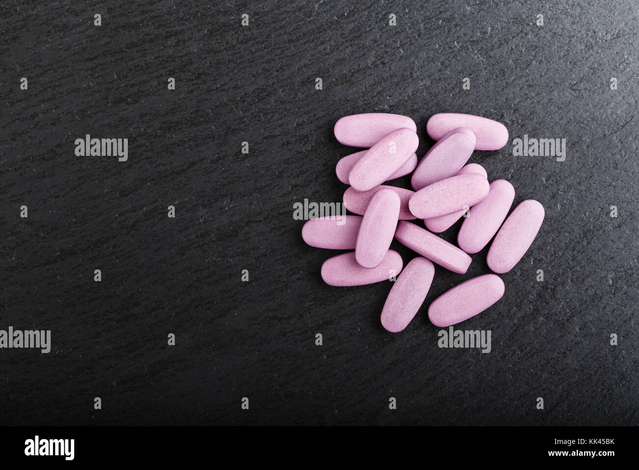 large pink tablets scattered on a black background Stock Photo - Alamy