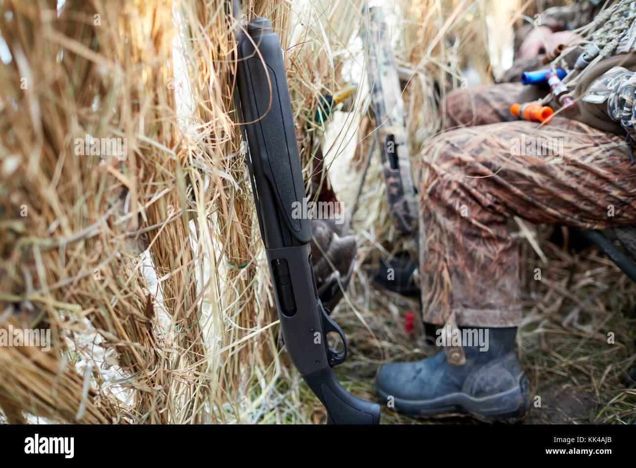 Hunters waiting inside a blind or hide seated on portable stools with ...