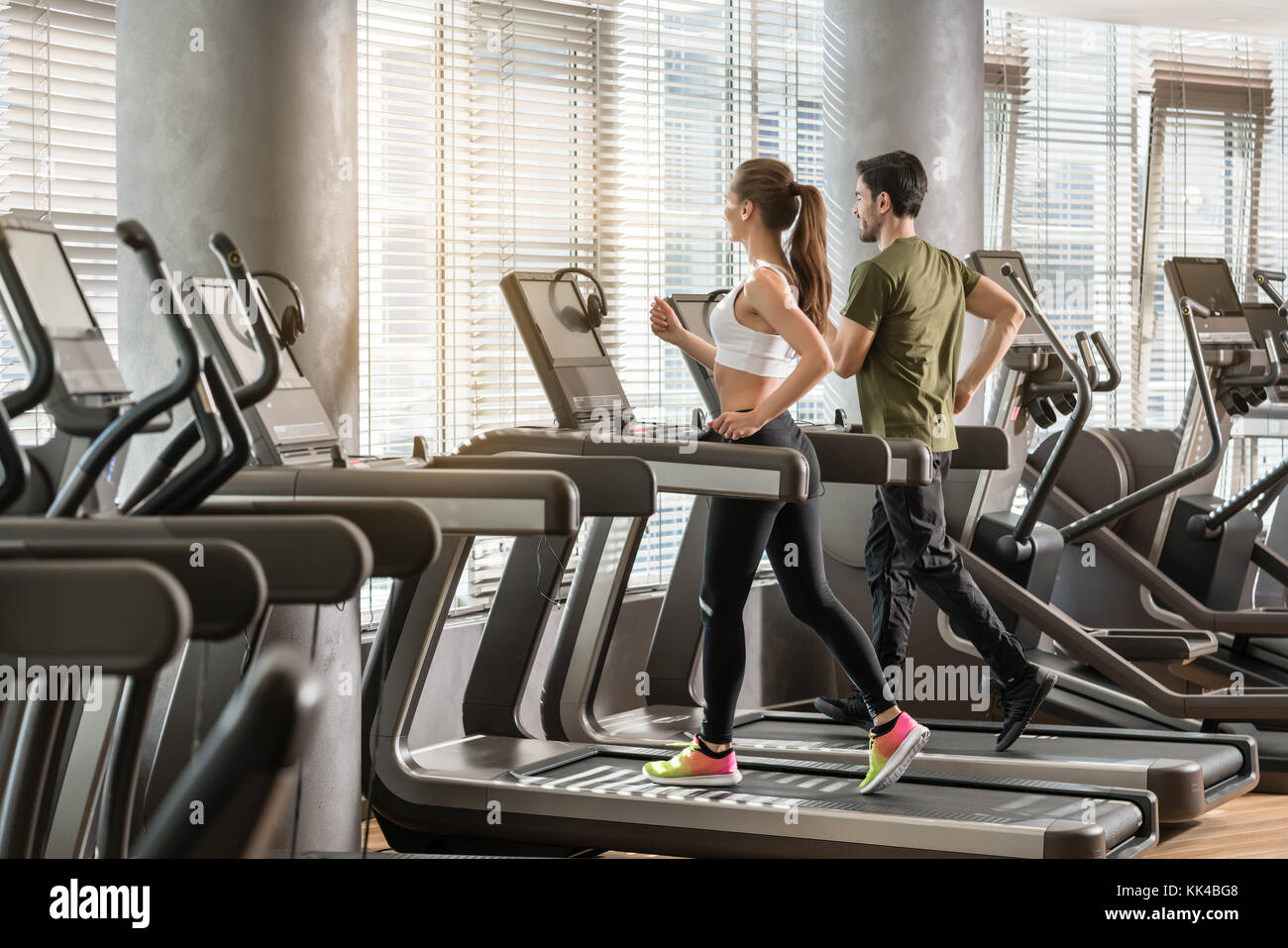 Young man and woman smiling while running side by side on electr Stock ...