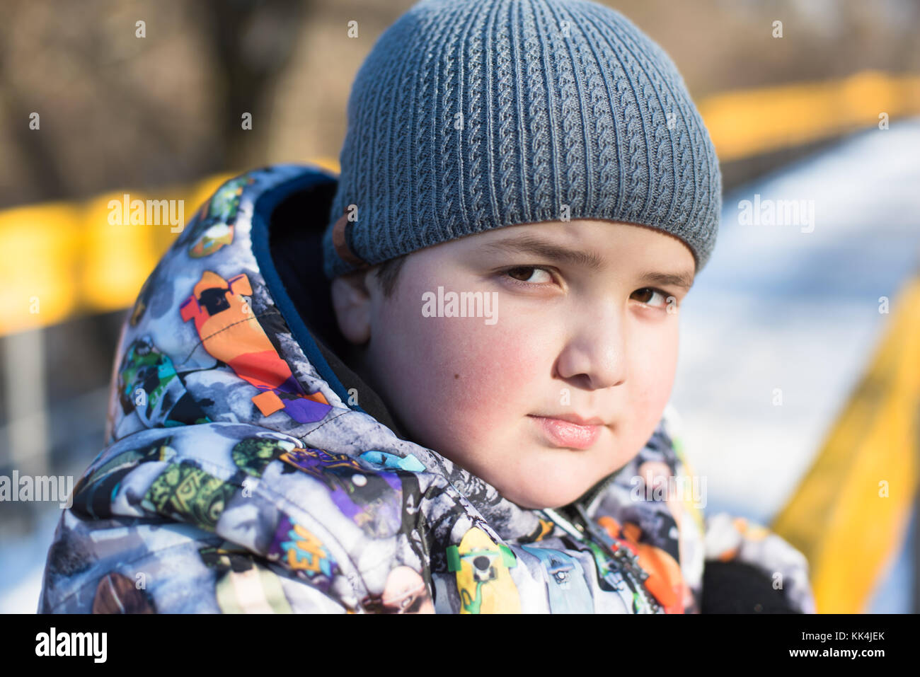 portrait of beautiful fat boy in cap and winter jacket in park in ...