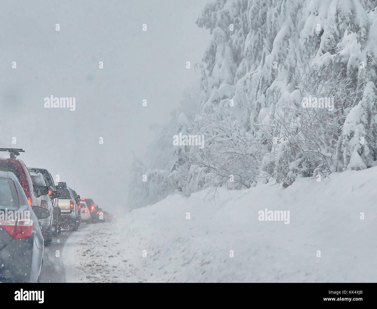 Winter storm driving showing back of a line of cars, snow drifts, snow ...