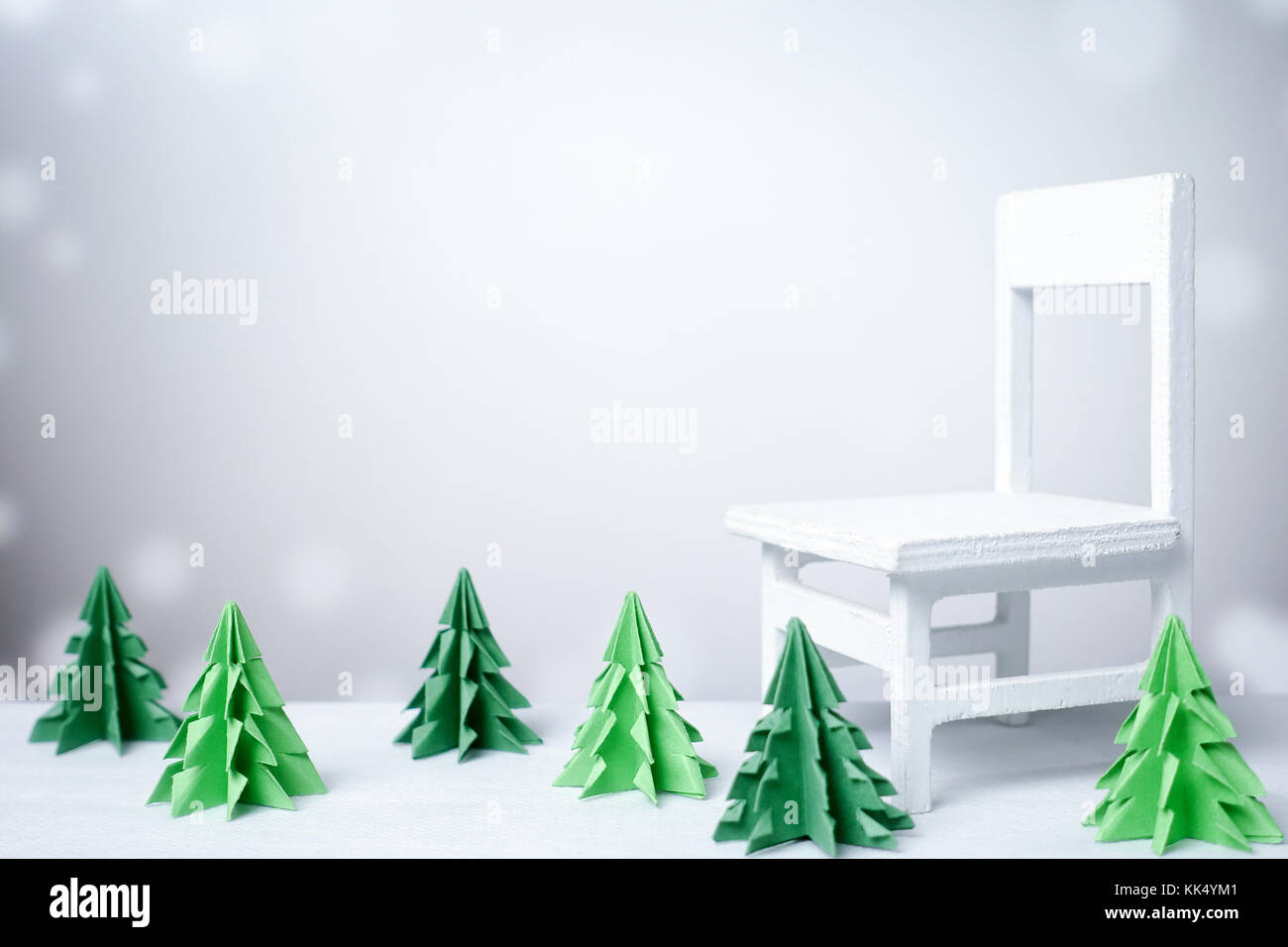 White chair in snowy winter background with paper cut christmas tree ...