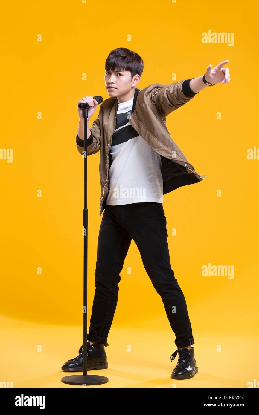 Cheerful young Chinese man singing with microphone Stock Photo - Alamy