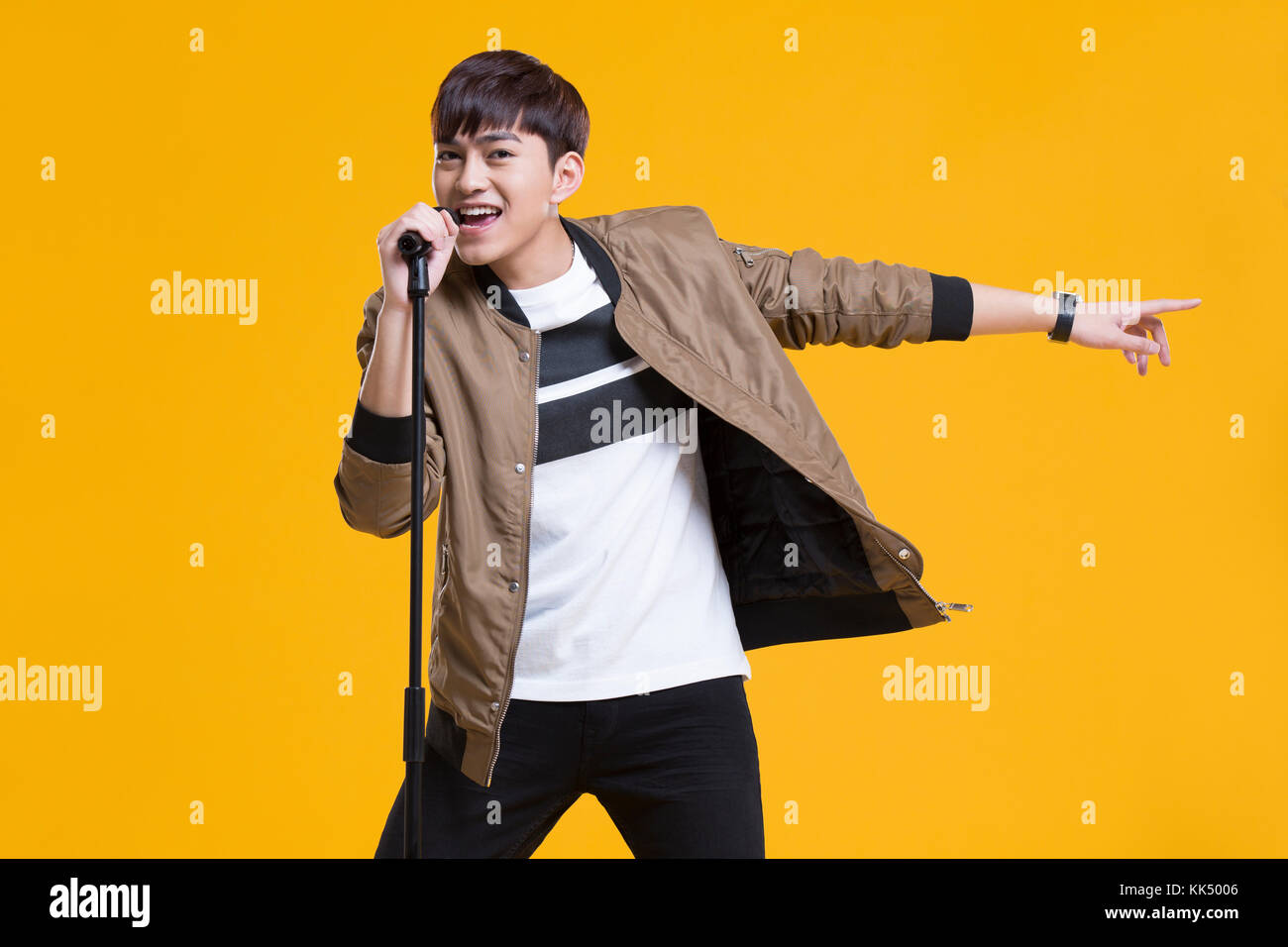 Cheerful young Chinese man singing with microphone Stock Photo - Alamy