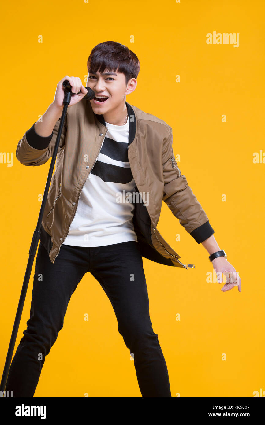 Cheerful young Chinese man singing with microphone Stock Photo - Alamy