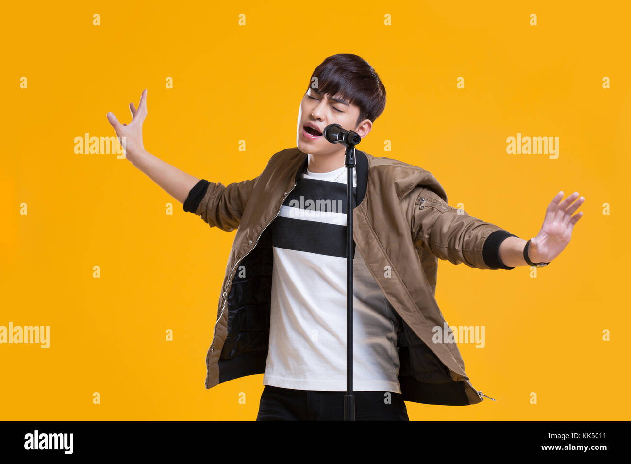 Cheerful young Chinese man singing with microphone Stock Photo - Alamy