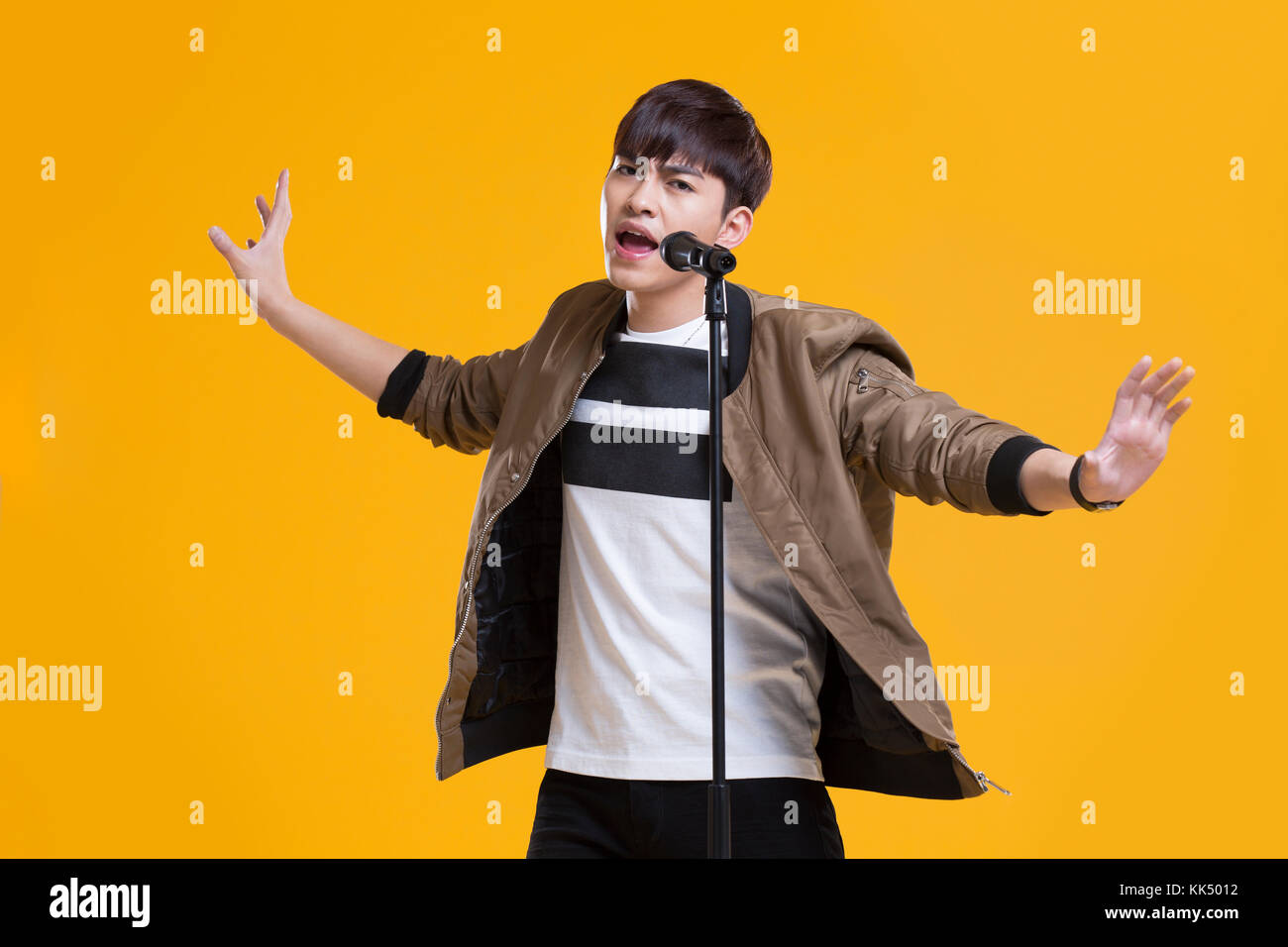 Cheerful young Chinese man singing with microphone Stock Photo - Alamy